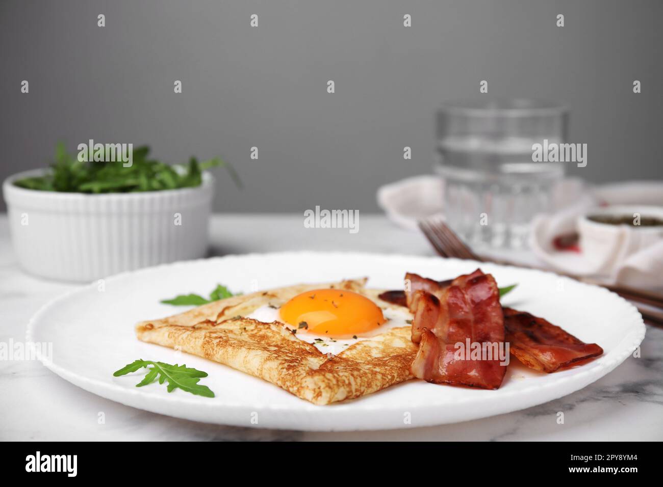 Delicious crepe with egg served on white marble table. Breton galette ...