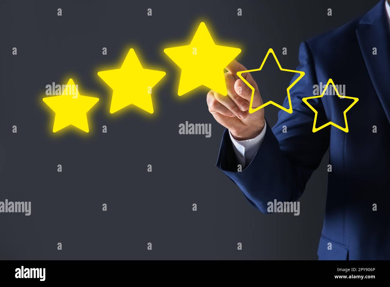 Man pointing at icons of stars on grey background, closeup. Quality ...