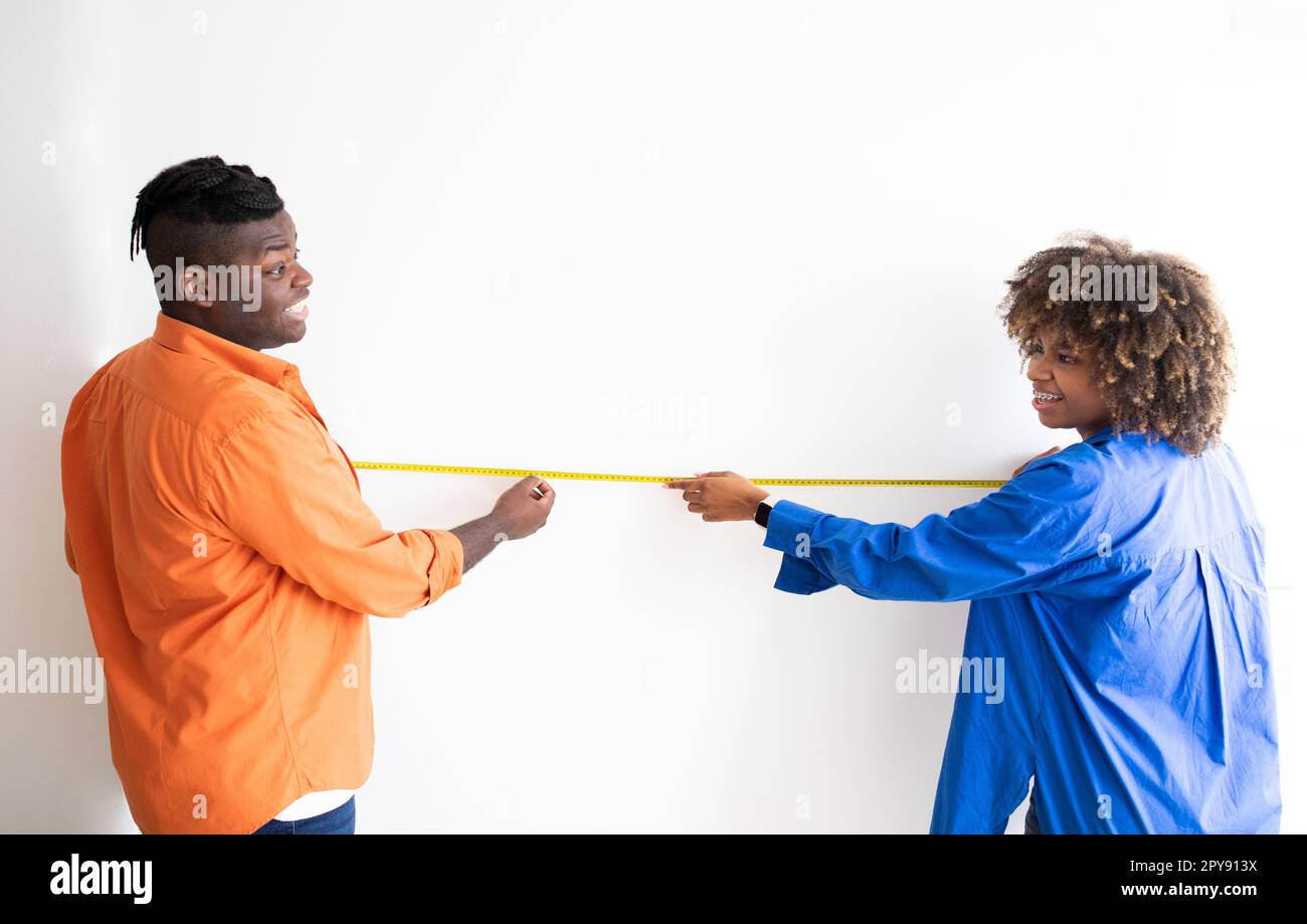 Happy black family couple measuring wall with tape ruler at home Stock ...