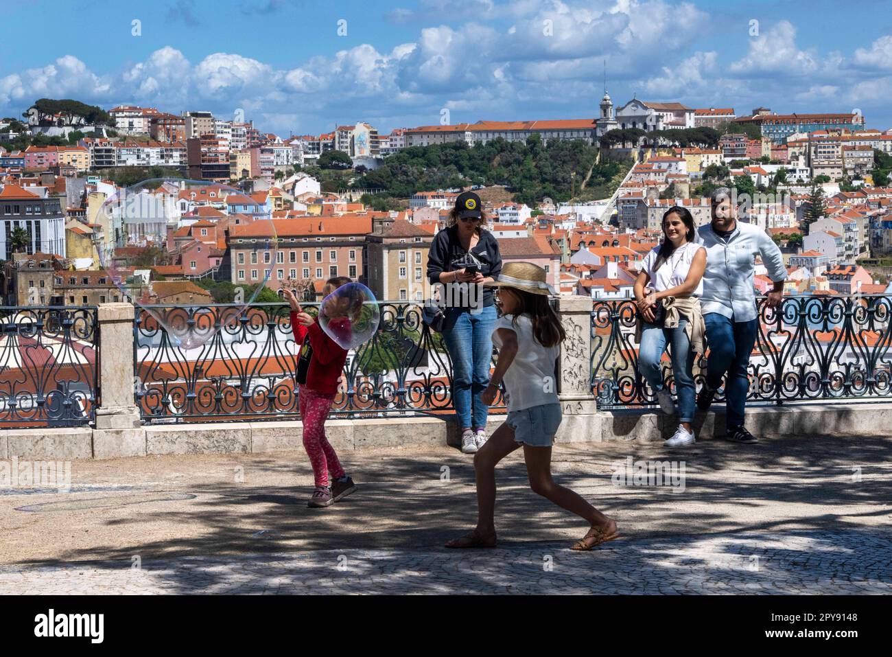 Children are seen playing with soap bubbles near some people at the ...
