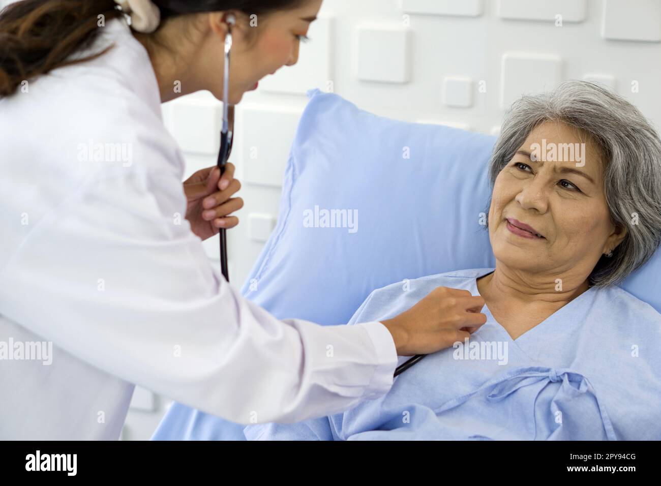 Senior female patient and doctor. Young asian doctor use a stethoscope ...