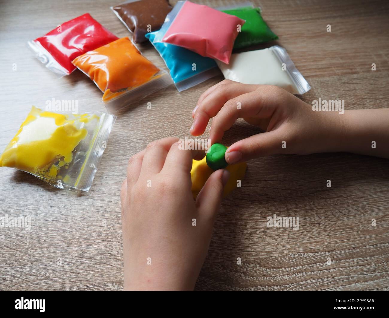 Children's hands crumple soft plasticine. Packages with plasticine are ...