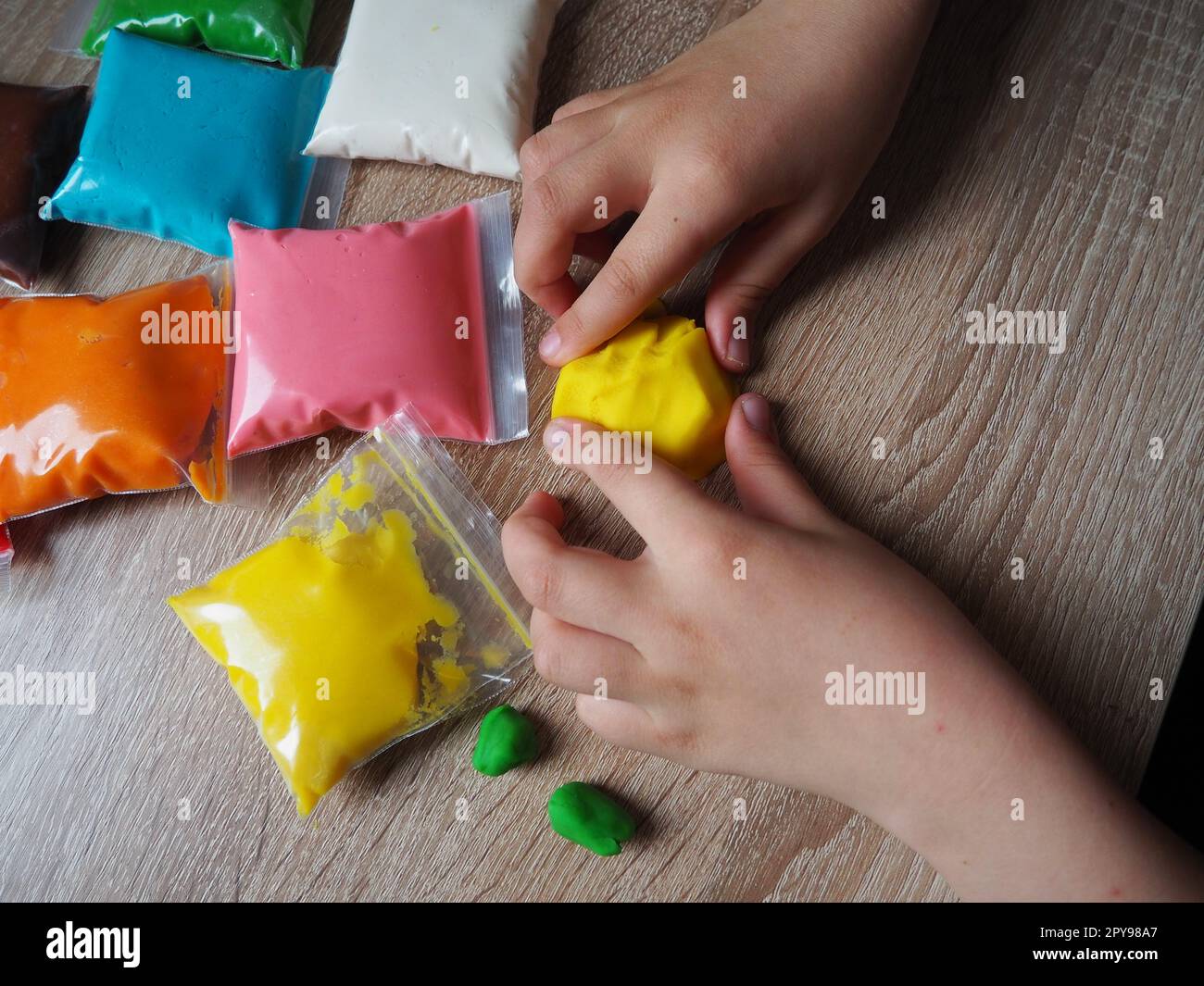 Children's hands crumple soft plasticine. Packages with plasticine are ...