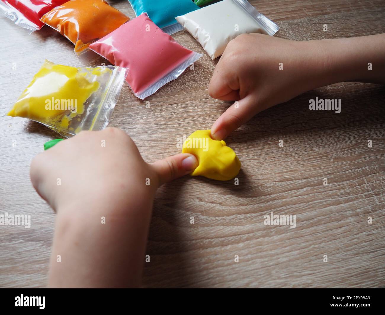 Children's hands crumple soft plasticine. Packages with plasticine are ...