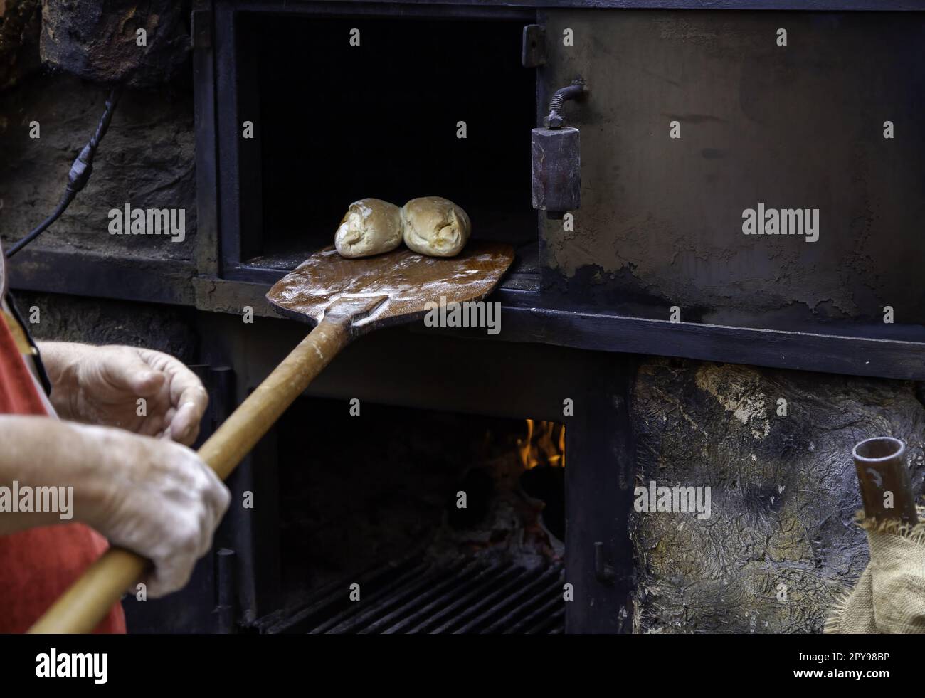 Baker preparing bread in oven hi-res stock photography and images - Alamy