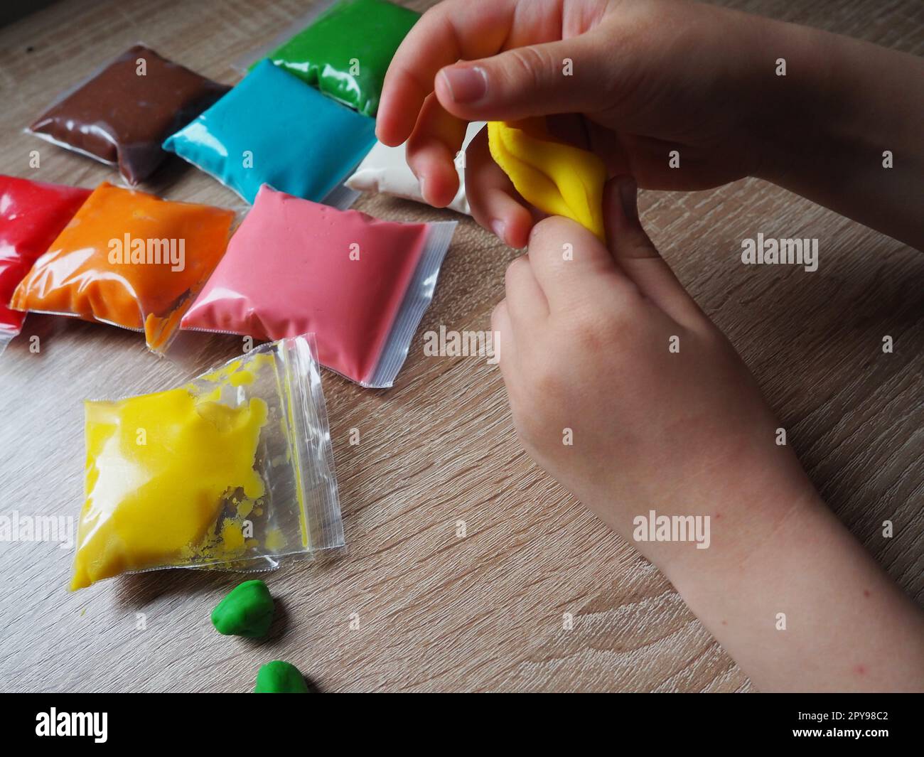 Children's hands crumple soft plasticine. Packages with plasticine are ...