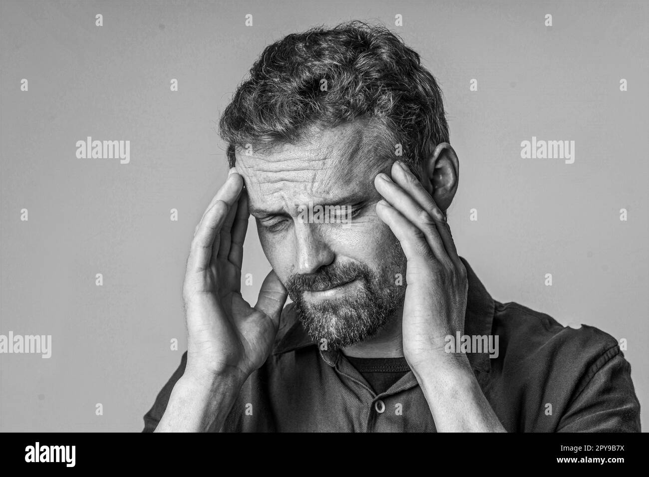 Man who appears to be in pain, holding his face with two hands against ...