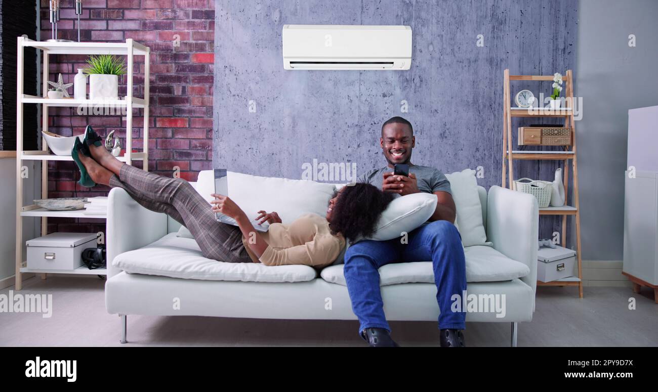 Happy Family Couple Using Air Conditioner Stock Photo - Alamy