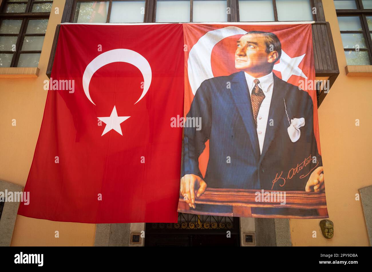 A Turkish flag and an equal-sized banner featuring a portrait of ...