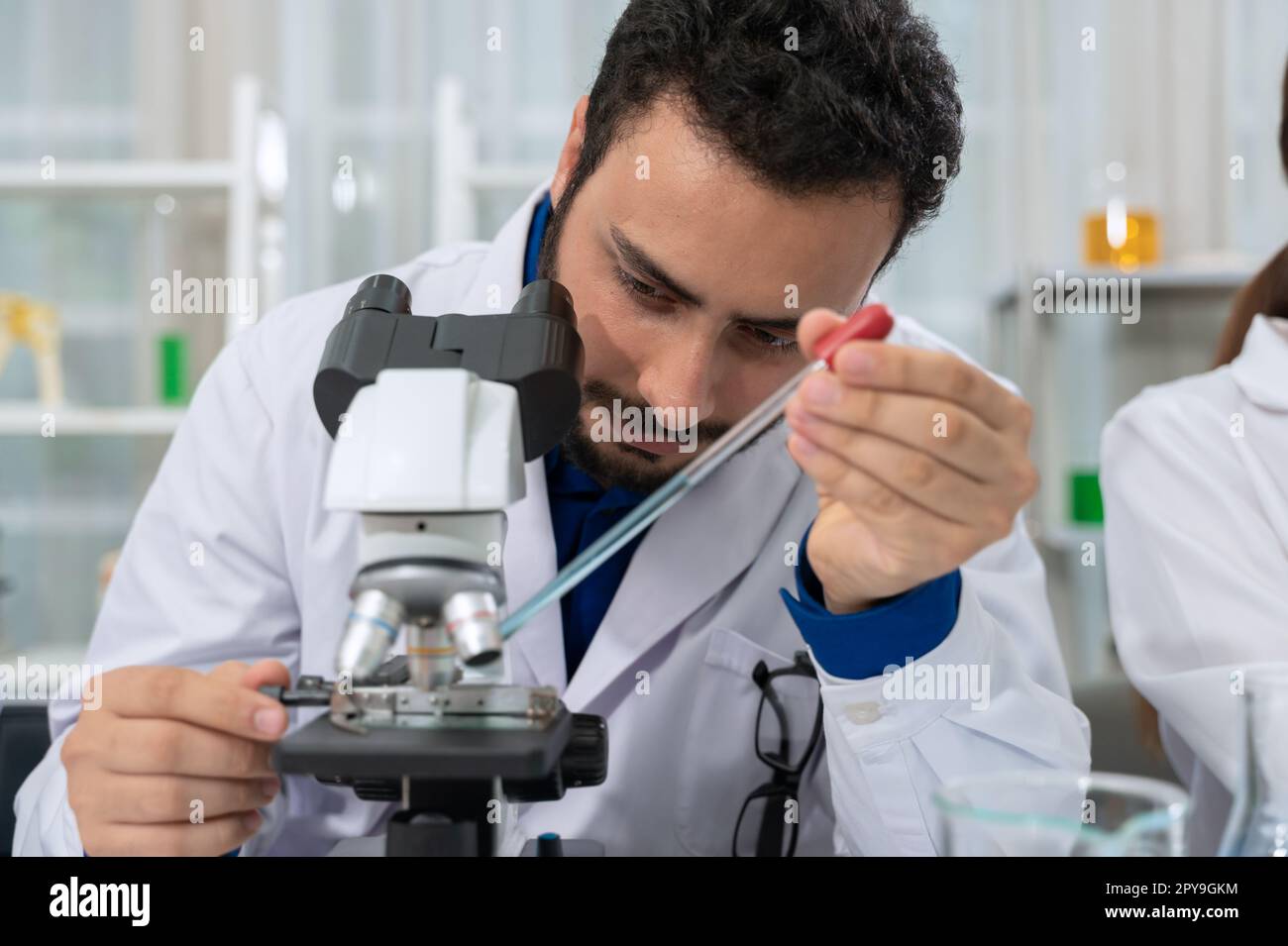 Male scientist dropping chemical liquid on slide at microscope. Science ...