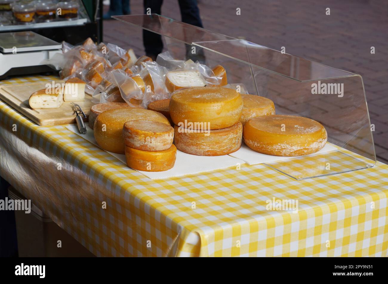 cheesemonger stand with rounds of Gouda and other cheeses at an open ...