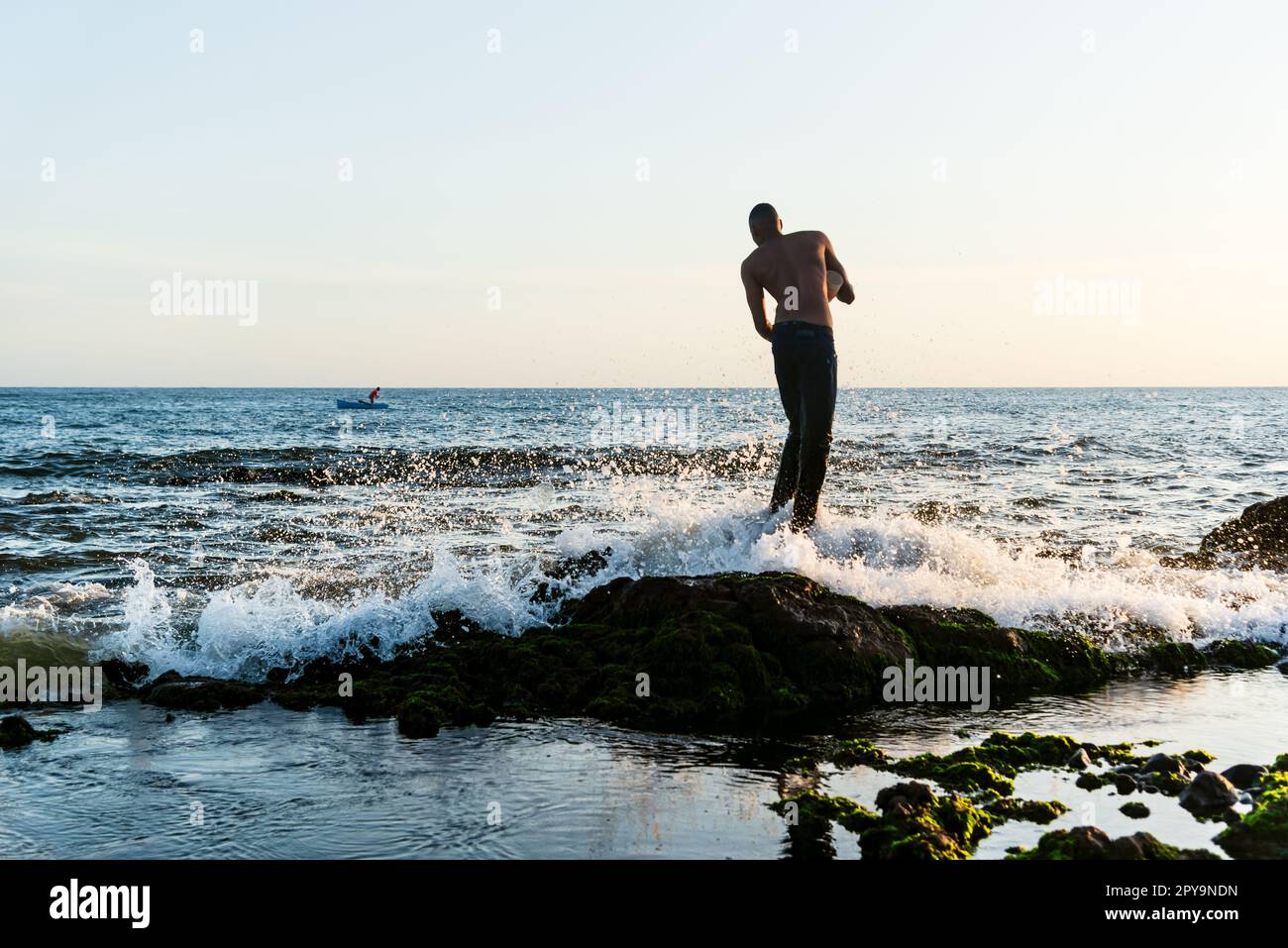 A fisherman on top of the rocks fishing. Late afternoon at Rio Vermelho ...