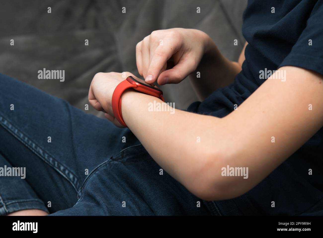 Red stylish smart watch on male wrist, side view closeup. Touch finger ...
