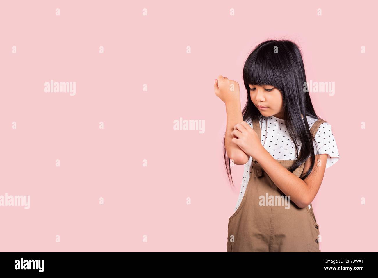 Asian little kid 10 years old scratching itch arm from a mosquito bite ...