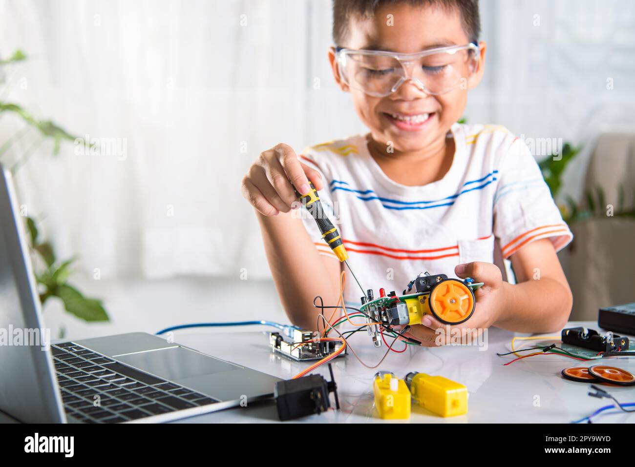 Asian kid boy assembling the Arduino robot car homework project at home ...