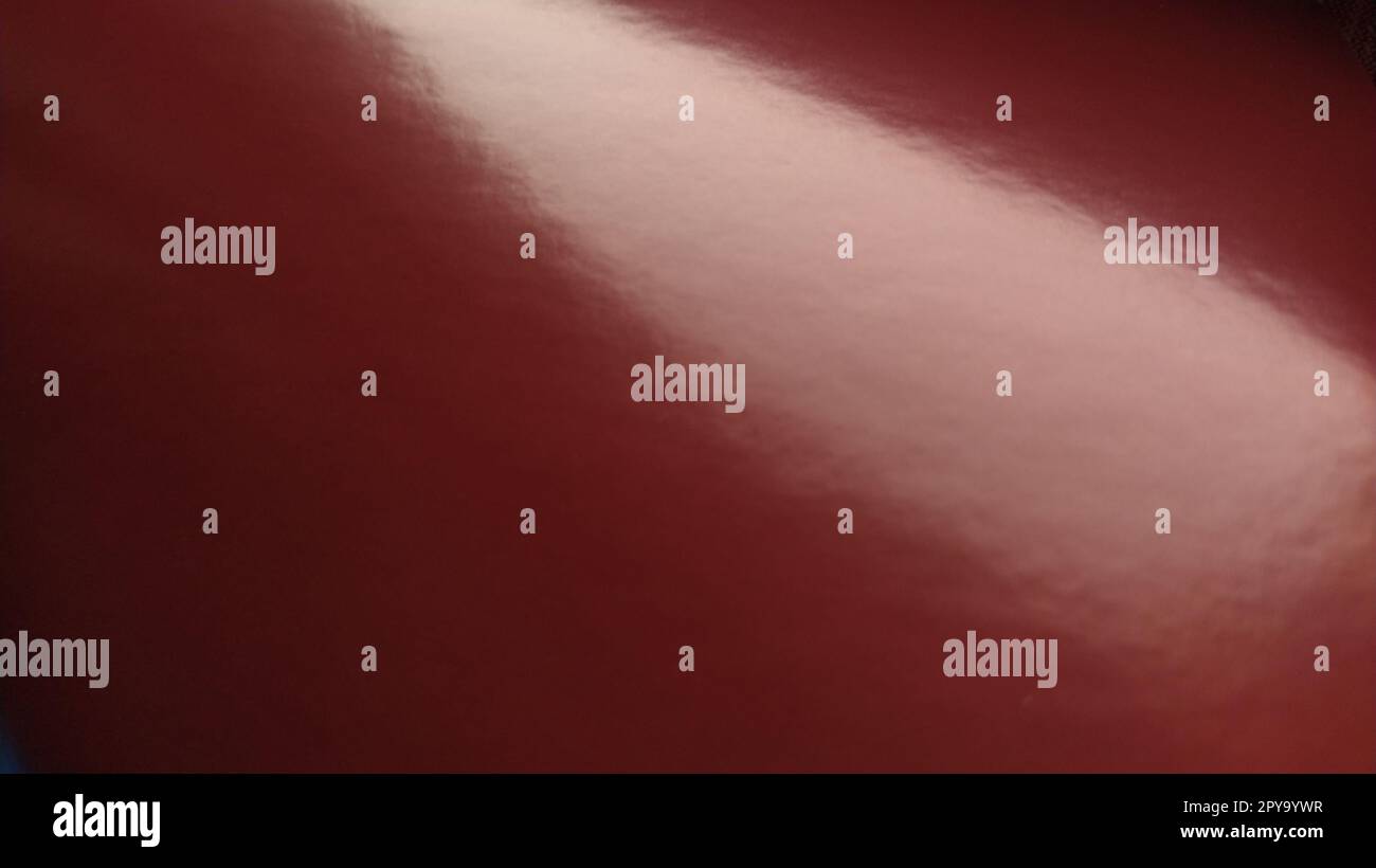 A long flare is a visage of light on shiny burgundy paper. Light spot ...