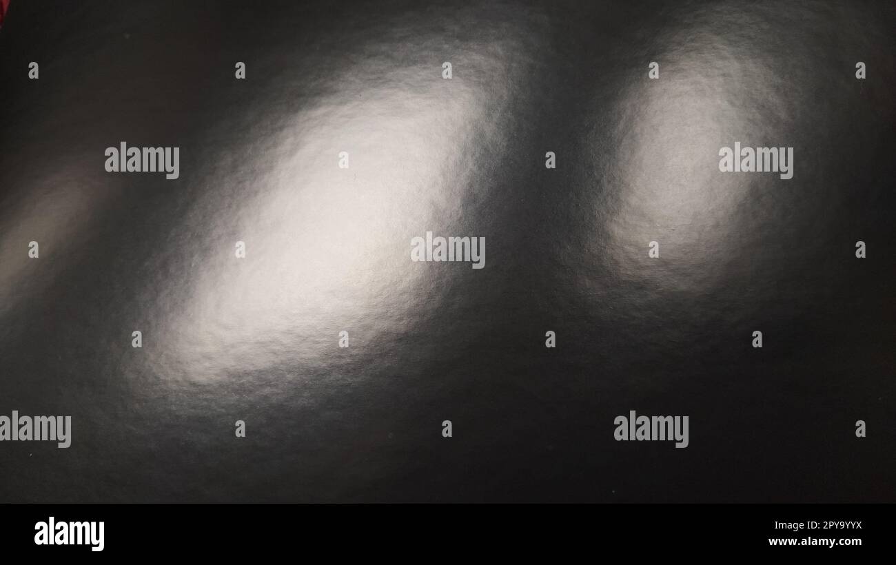 Glare of light on shiny gray paper. Several light spots on a dark surface that reflects light ...
