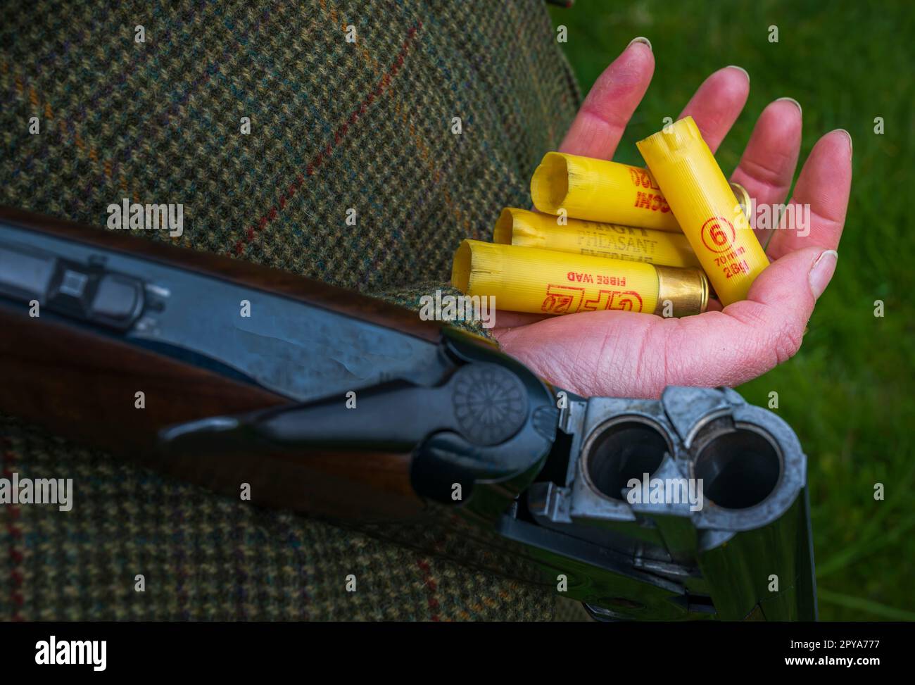 A close-up of a woman’s hand holding an open shotgun and a handful of ...