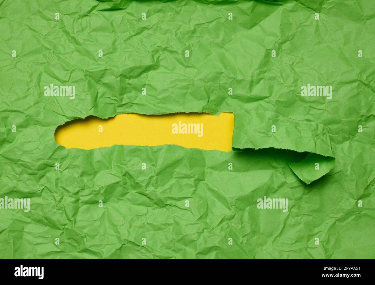Texture of crumpled green paper with torn hole and yellow background ...