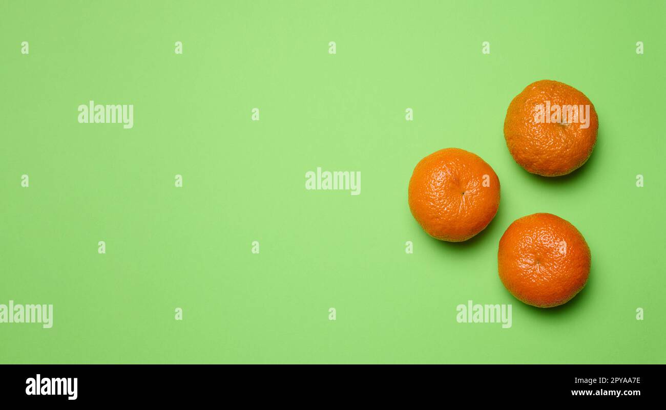 Three ripe mandarins on green background, top view. Ripe fruit Stock ...