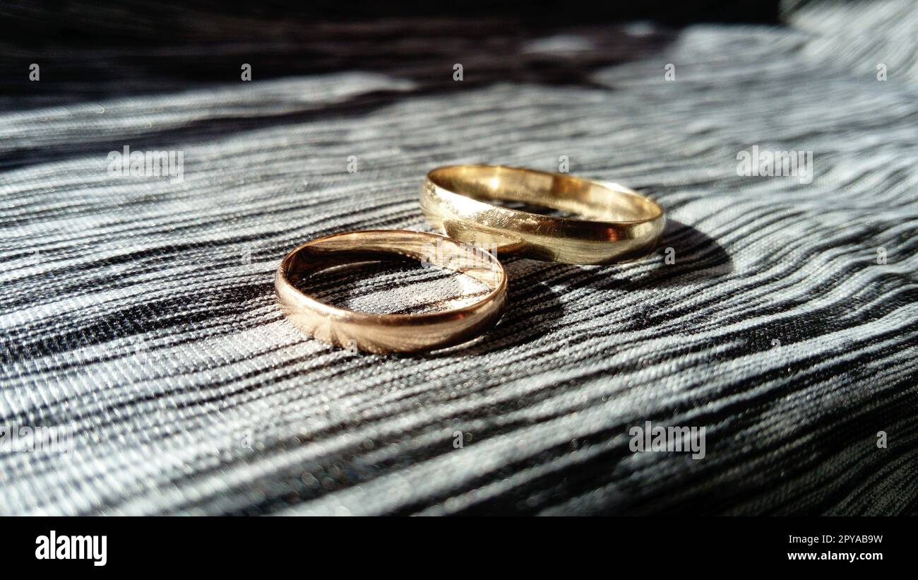 two gold wedding rings on a polo background with reflections of the ...