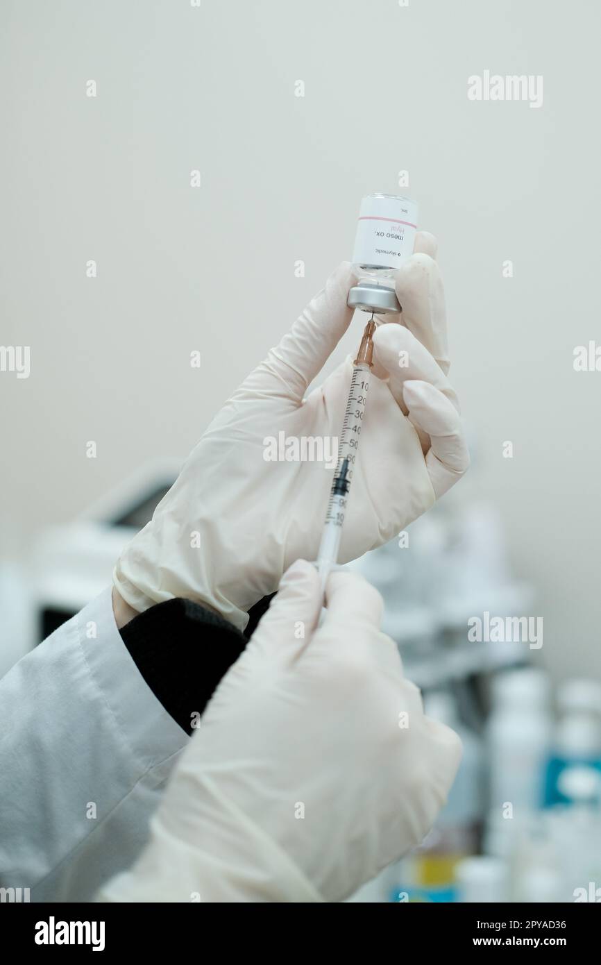 Cosmetologist putting mesotherapy serum on syringe from serum bottle ...