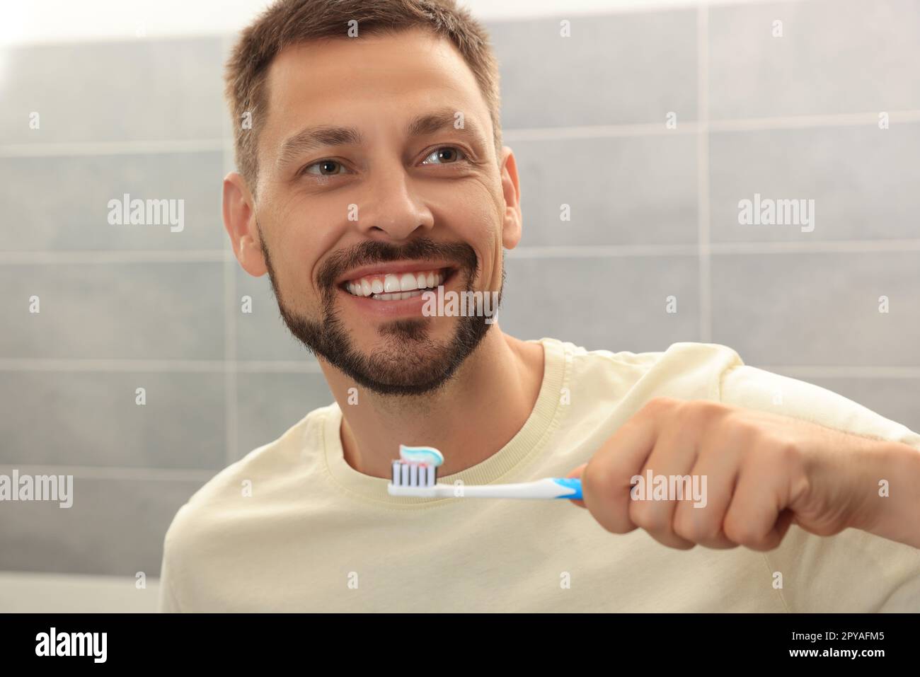 Man holding brush with toothpaste in bathroom Stock Photo - Alamy