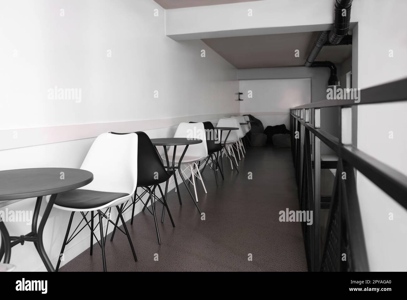 Hostel dining room interior with tables and chairs along white wall ...