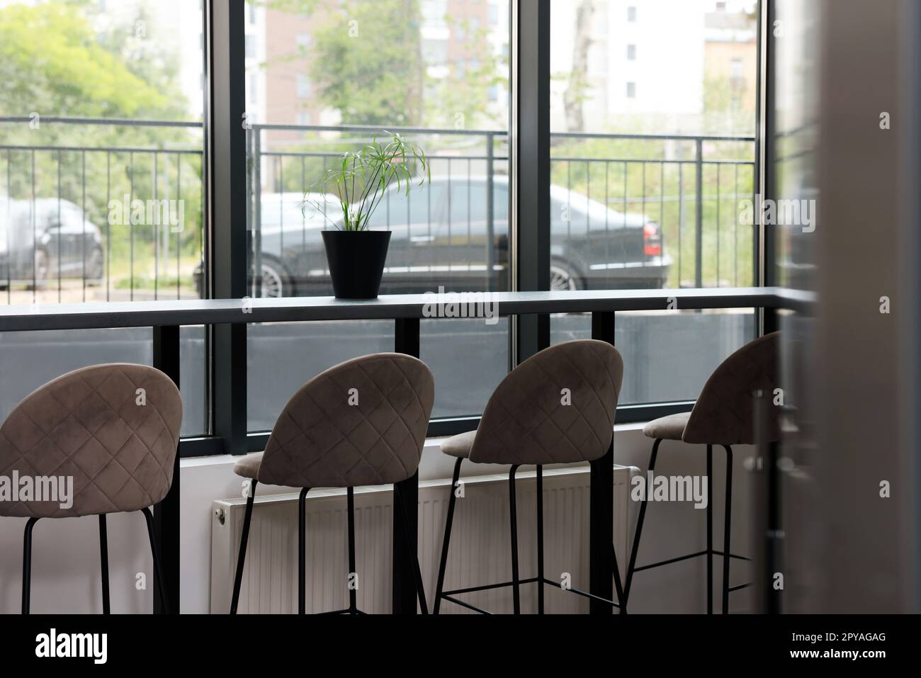 Table and bar stools near window in hostel dining room Stock Photo - Alamy