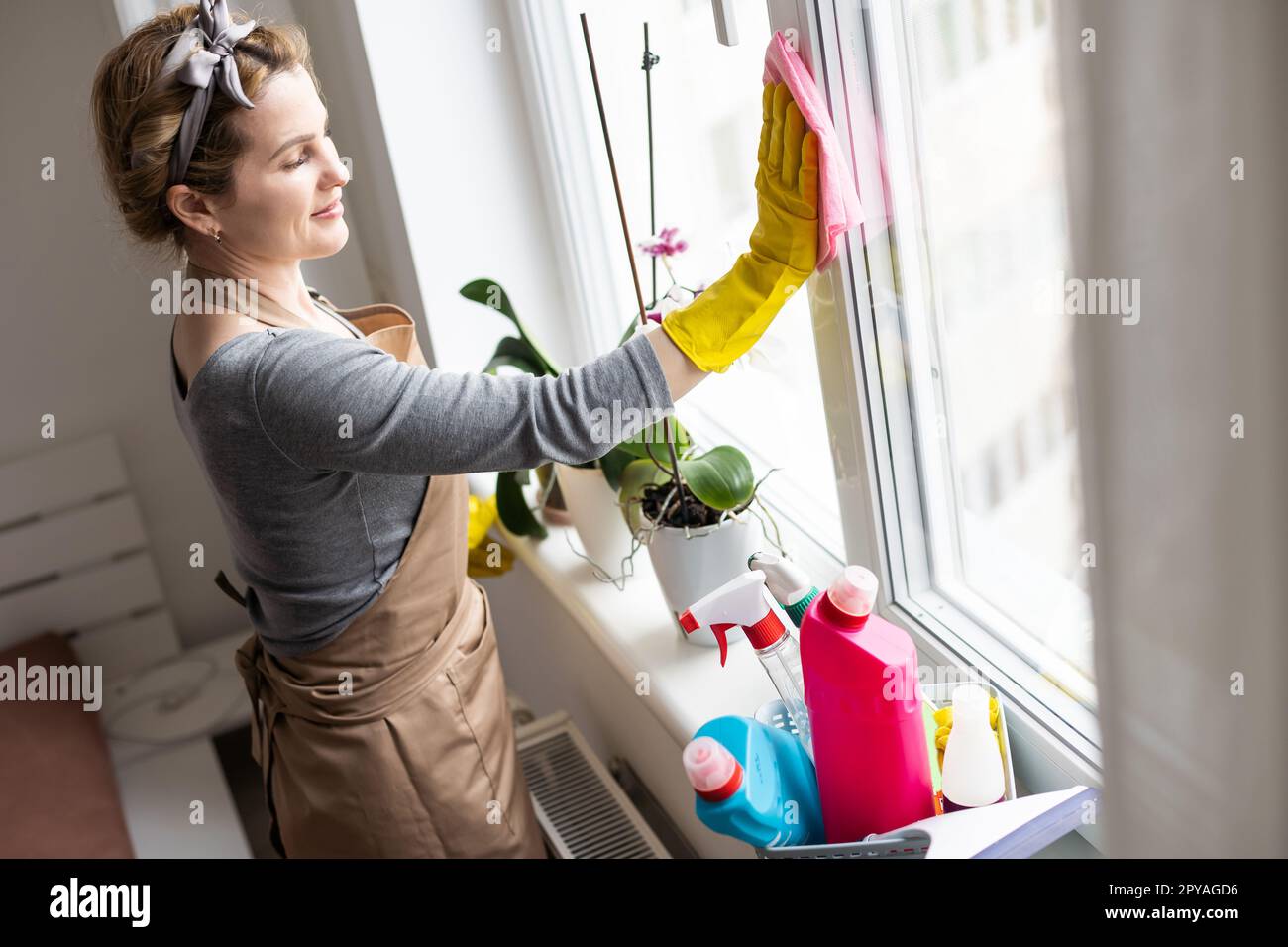 Woman cleaning and polishing the kitchen worktop with a spray detergent ...