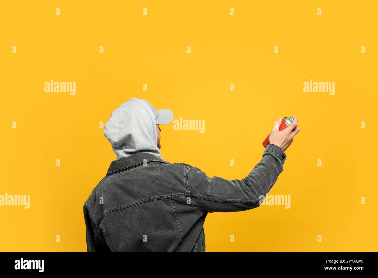 Man holding can of spray paint on yellow background, back view Stock ...