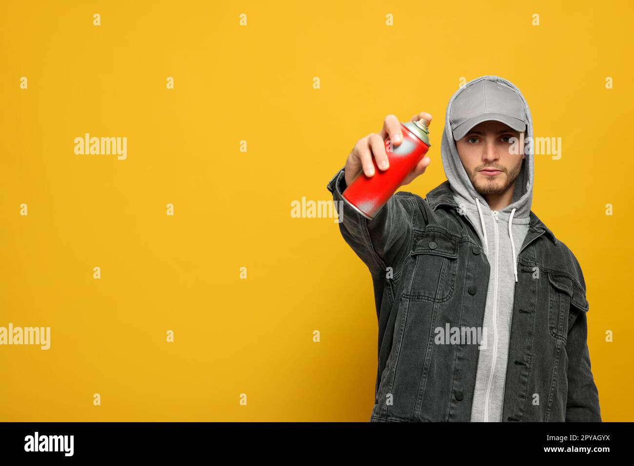 Handsome man holding can of spray paint on yellow background. Space for ...