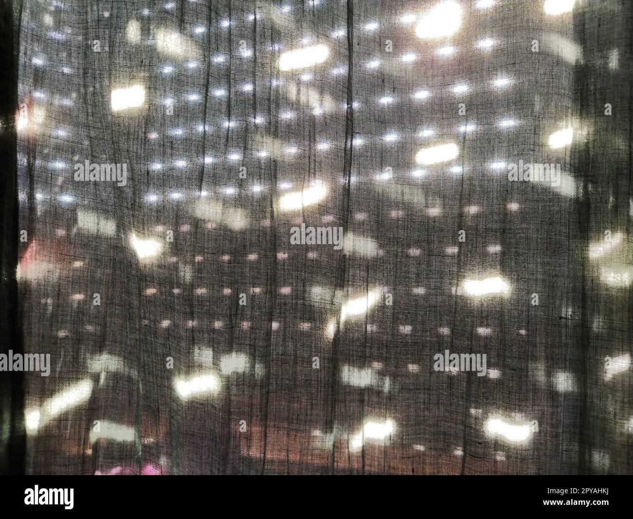 Sunlight shines through blinds with small holes and gray curtains ...