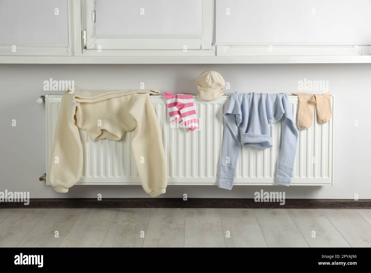 Clean clothes on heating radiator near window indoors Stock Photo - Alamy