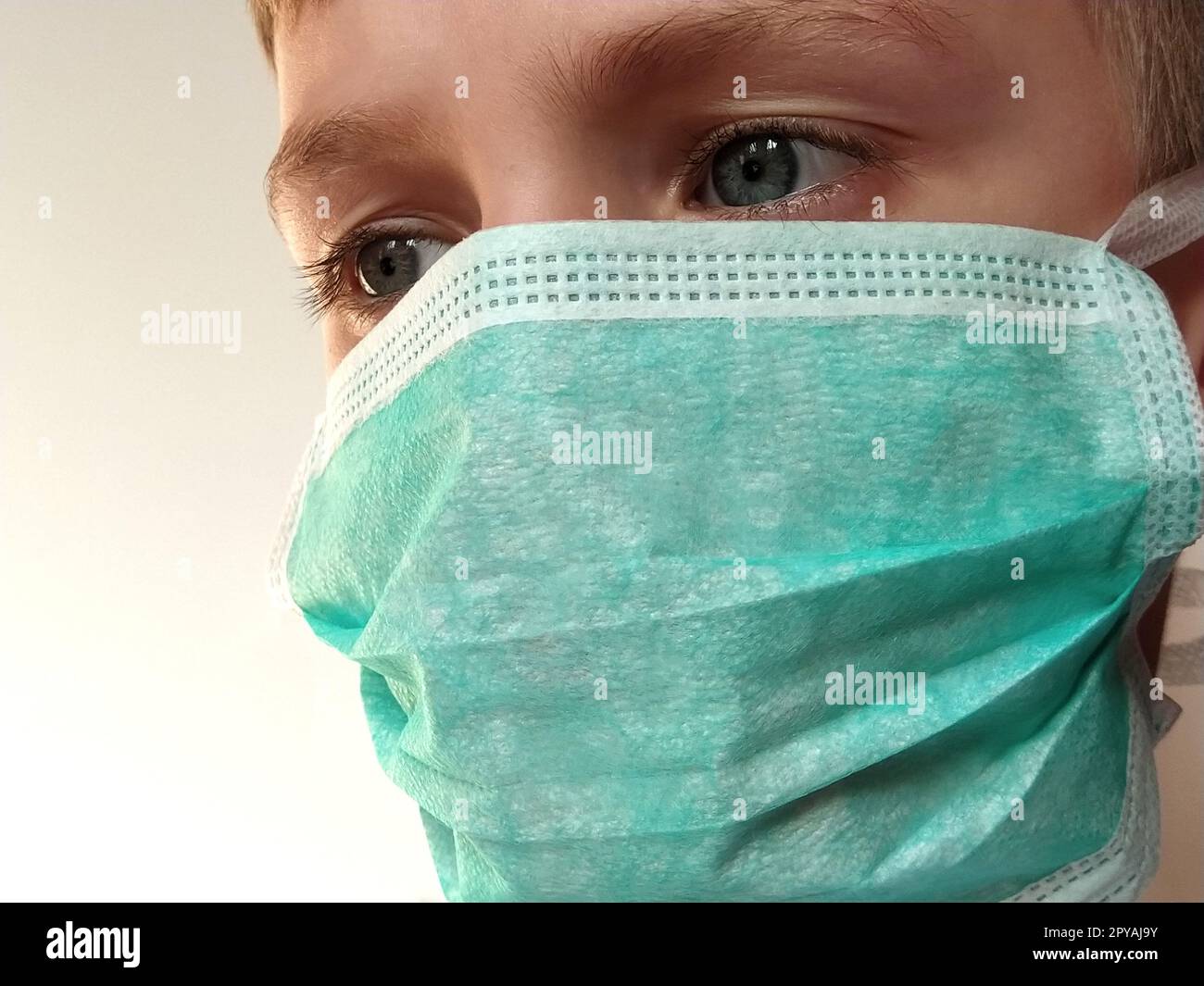 Masked child. The face of a 7-year-old boy in a protective surgical ...