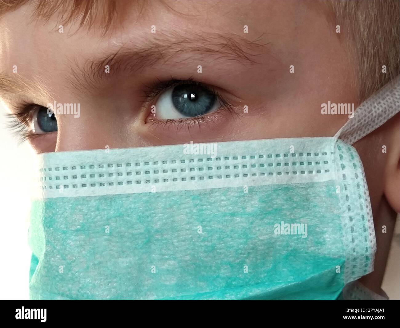 Masked child. The face of a 7-year-old boy in a protective surgical ...