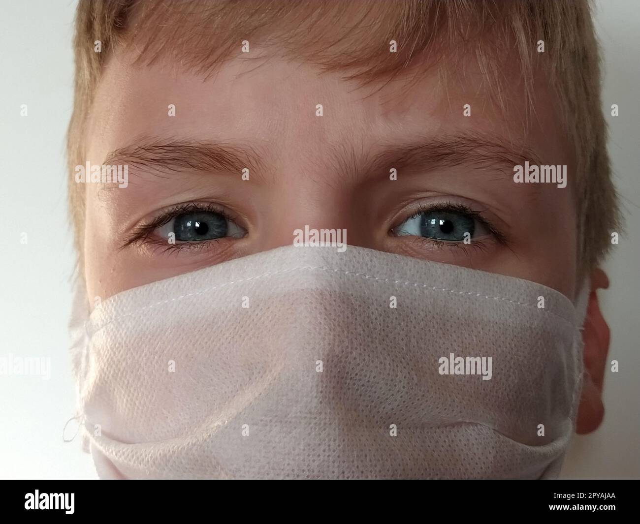 Masked child. The face of a 7-year-old boy in a protective white ...