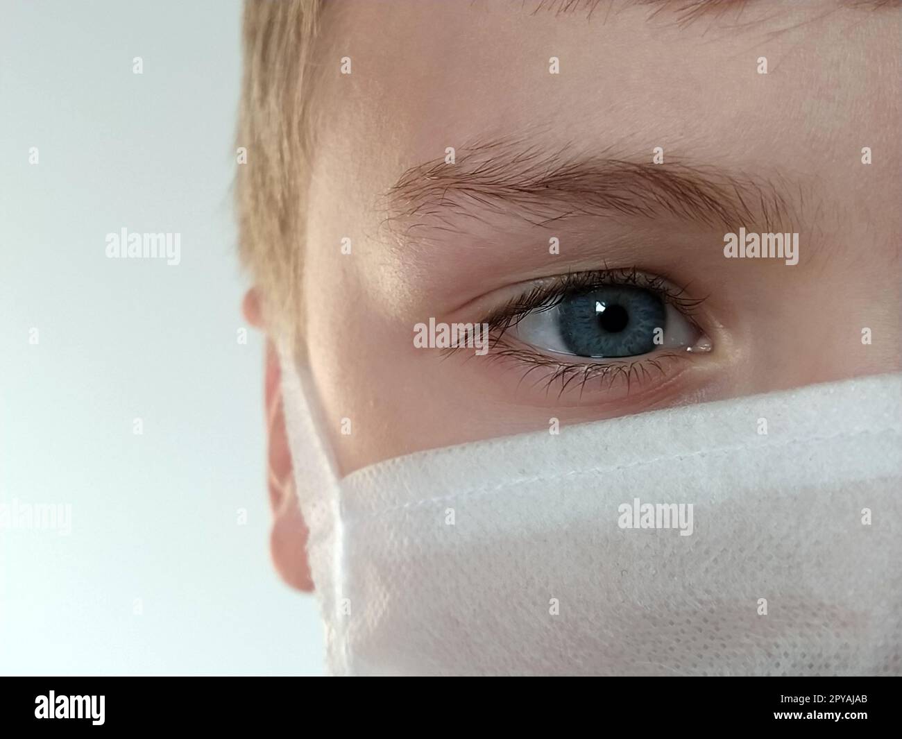 Masked child. The face of a 7-year-old boy in a protective white ...