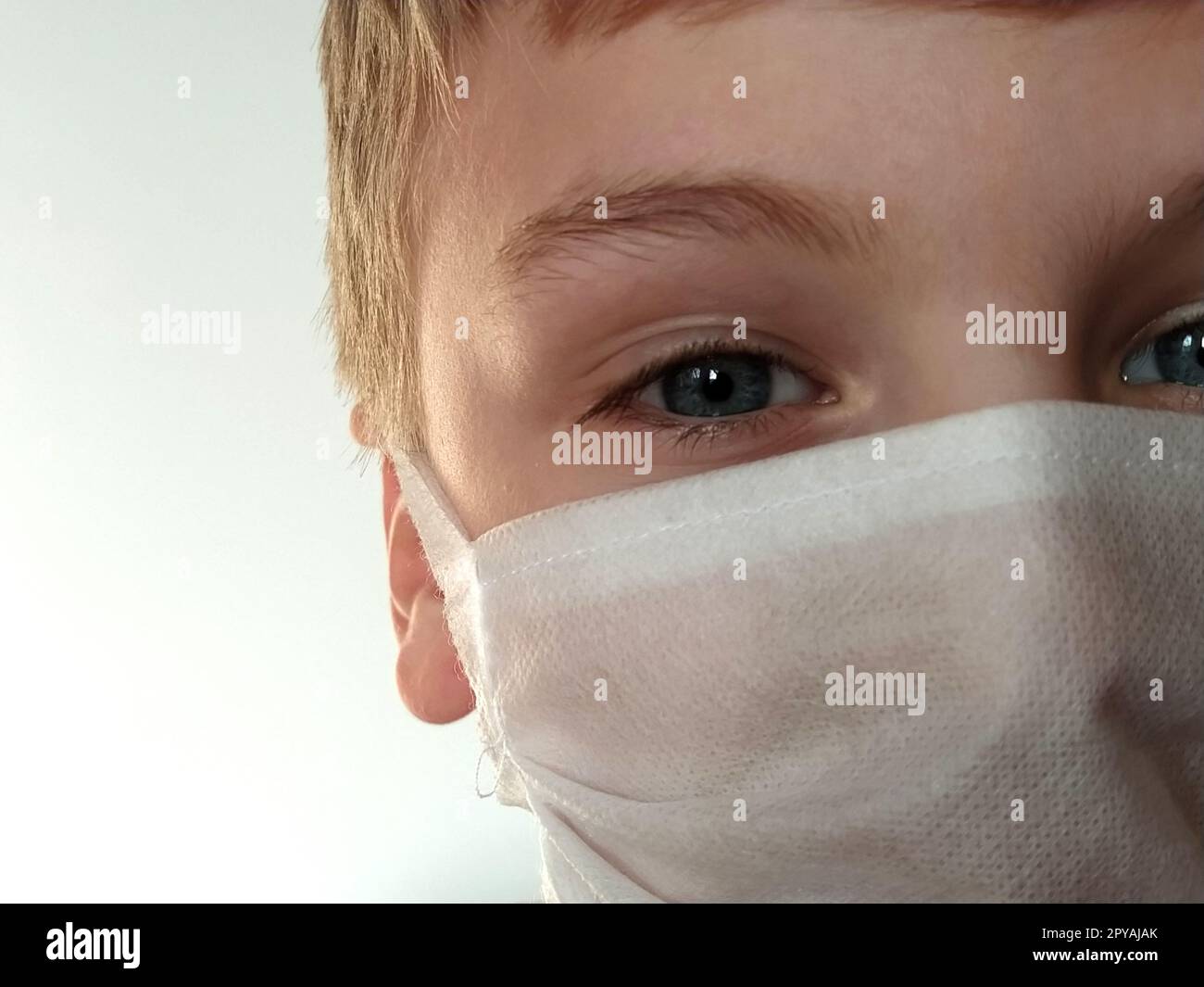 Masked child. The face of a 7-year-old boy in a protective white ...