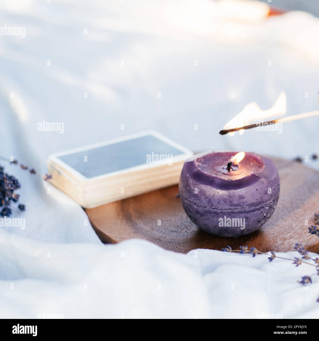 Match lights candle with next to deck of cards and lavender flowers, on ...