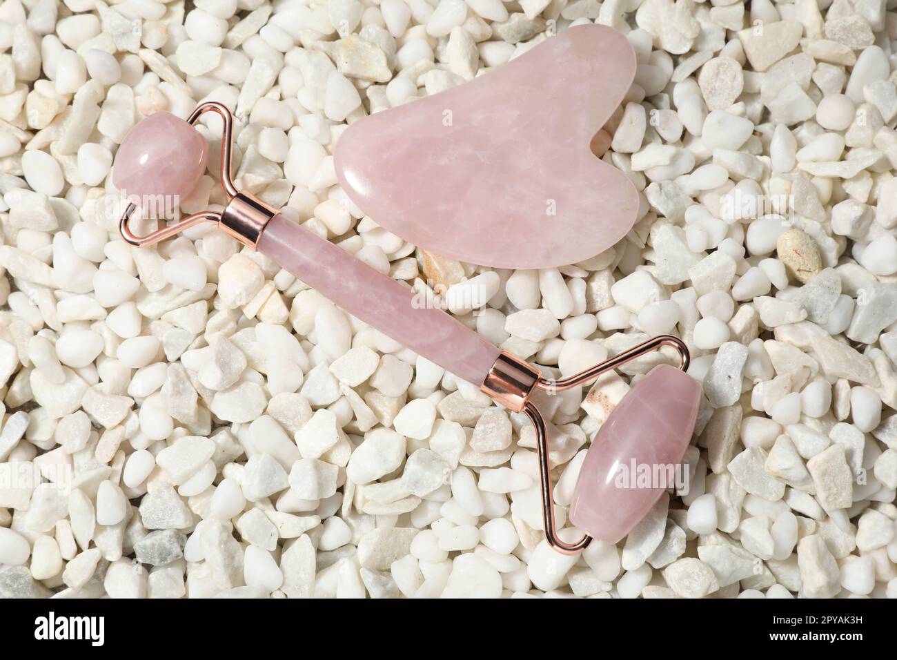 Quartz gua sha tool and face roller on white stones, flat lay Stock ...