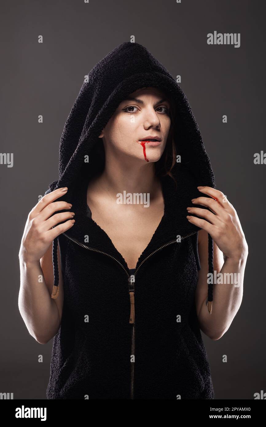 Angry girl with black hoodie and blood on her mouth. Lady in pain ...