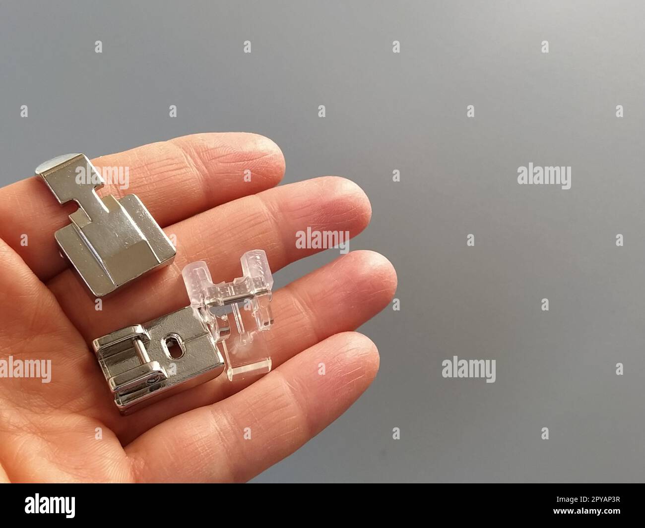 A set of feet for an electric sewing machine in a female hand. Gray ...