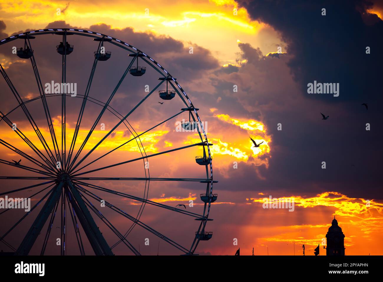 Ferris Wheel and illuminations in amusement park during scenic sunset ...