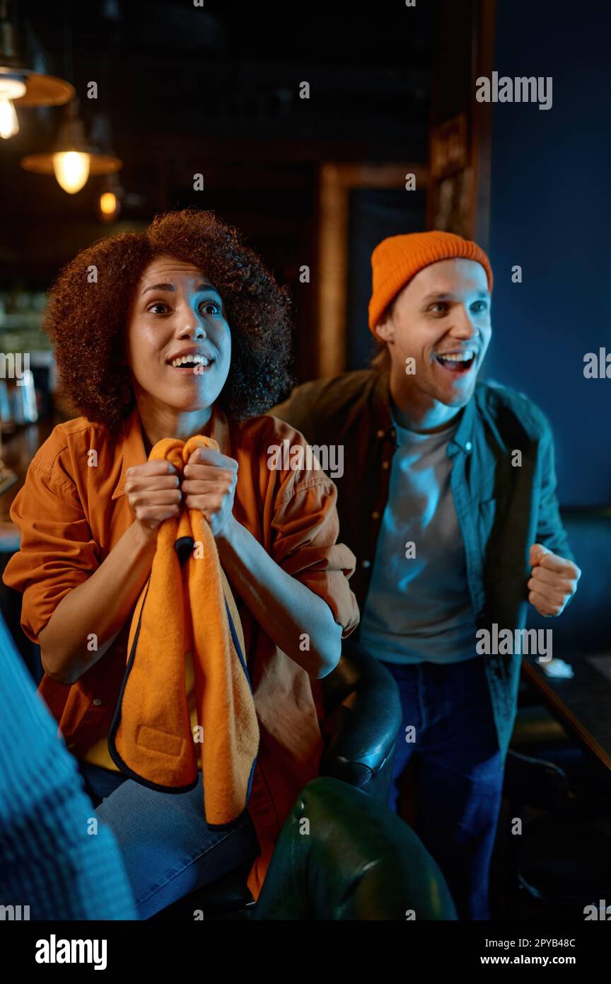 Group of young friends watching TV and support team while resting in ...