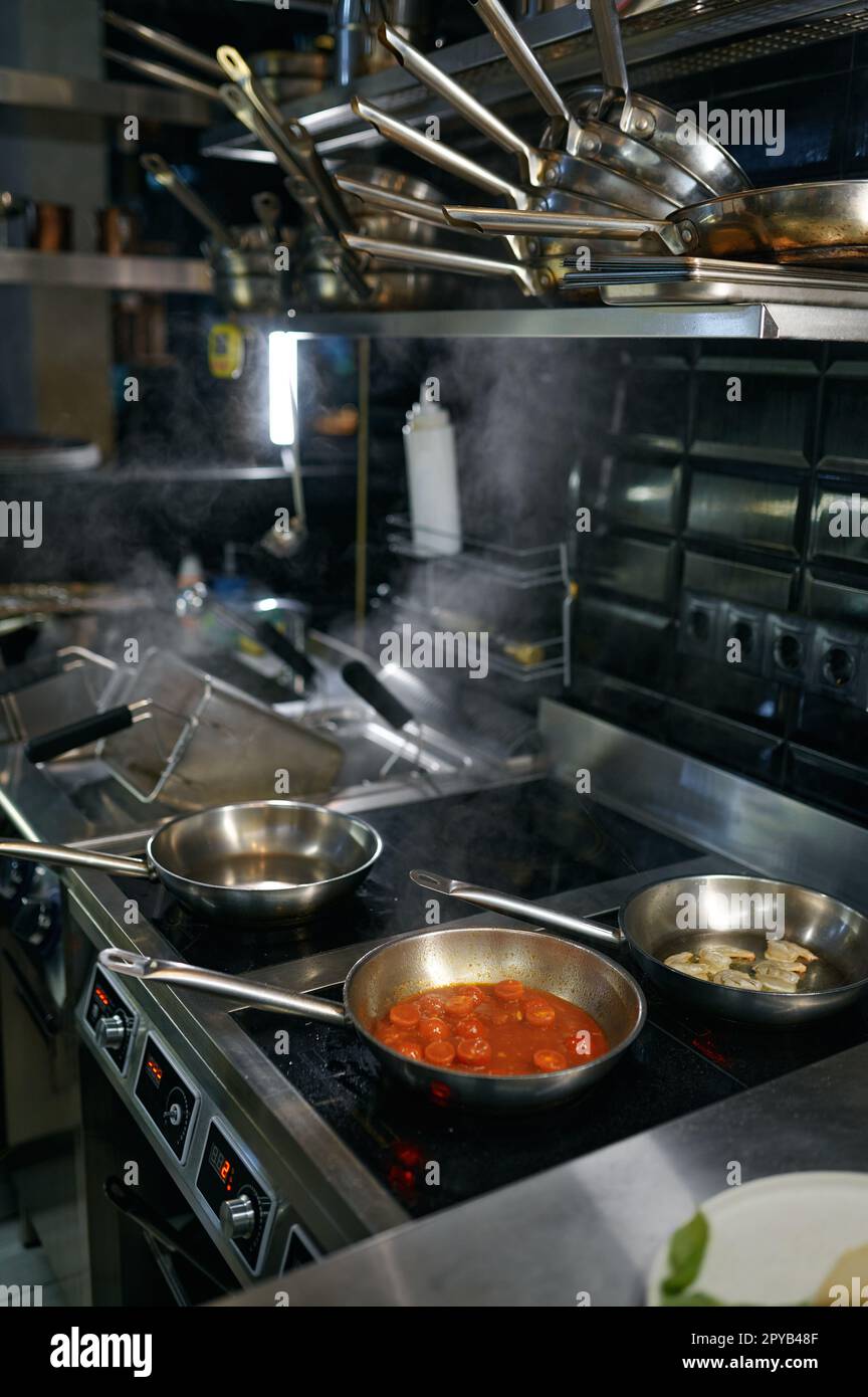 Traditional vegetarian pasta cooking at modern kitchen gas stove in wok ...