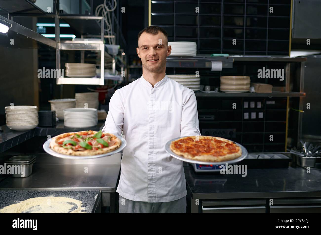 Master chef presenting two kinds of freshly cooked pizza Stock Photo ...