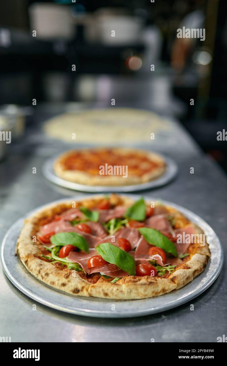Stages of pizza preparation with selective focus on freshly baked ...