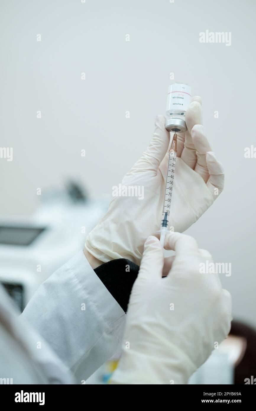 Cosmetologist putting mesotherapy serum on syringe from serum bottle ...