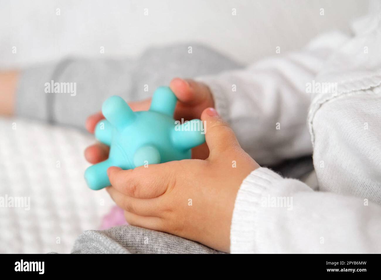 Cute baby girl playing tactile knobby balls. Young child hand plays ...
